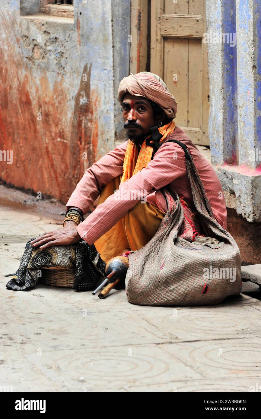 Thoughtful man in traditional dress sitting on a busy street, Varanasi ...