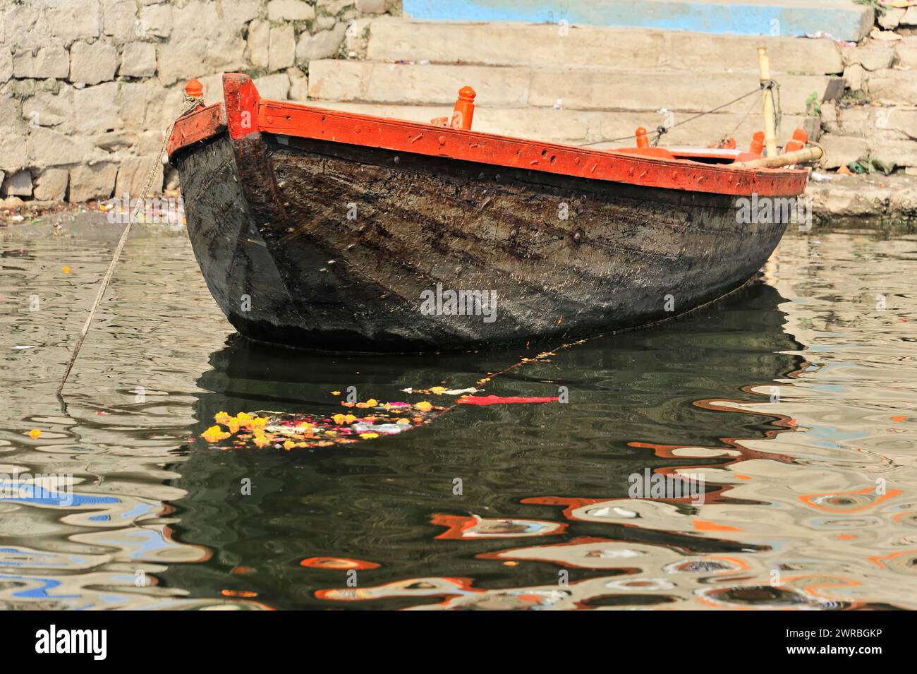 A single boat floats with a flower offering on the calm waters of a ...