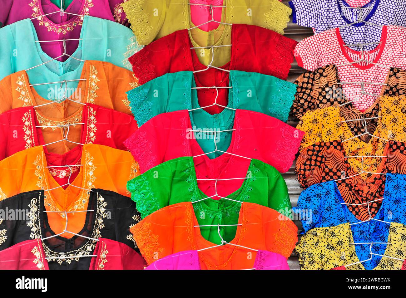 Row of colourful embroidered dresses on display at a market, Varanasi ...