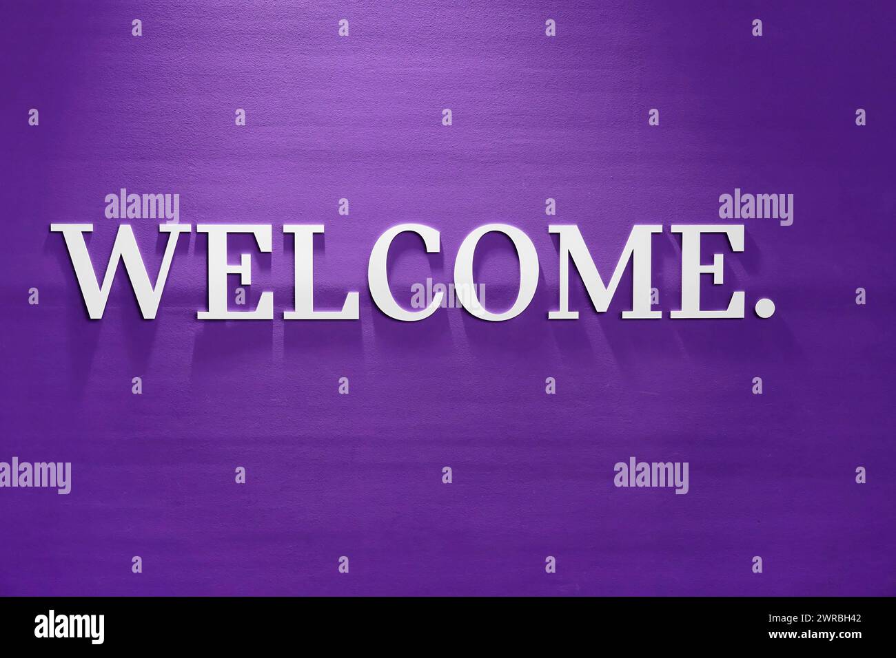 A simple purple wall with 'WELCOME.' in white lettering as a greeting ...