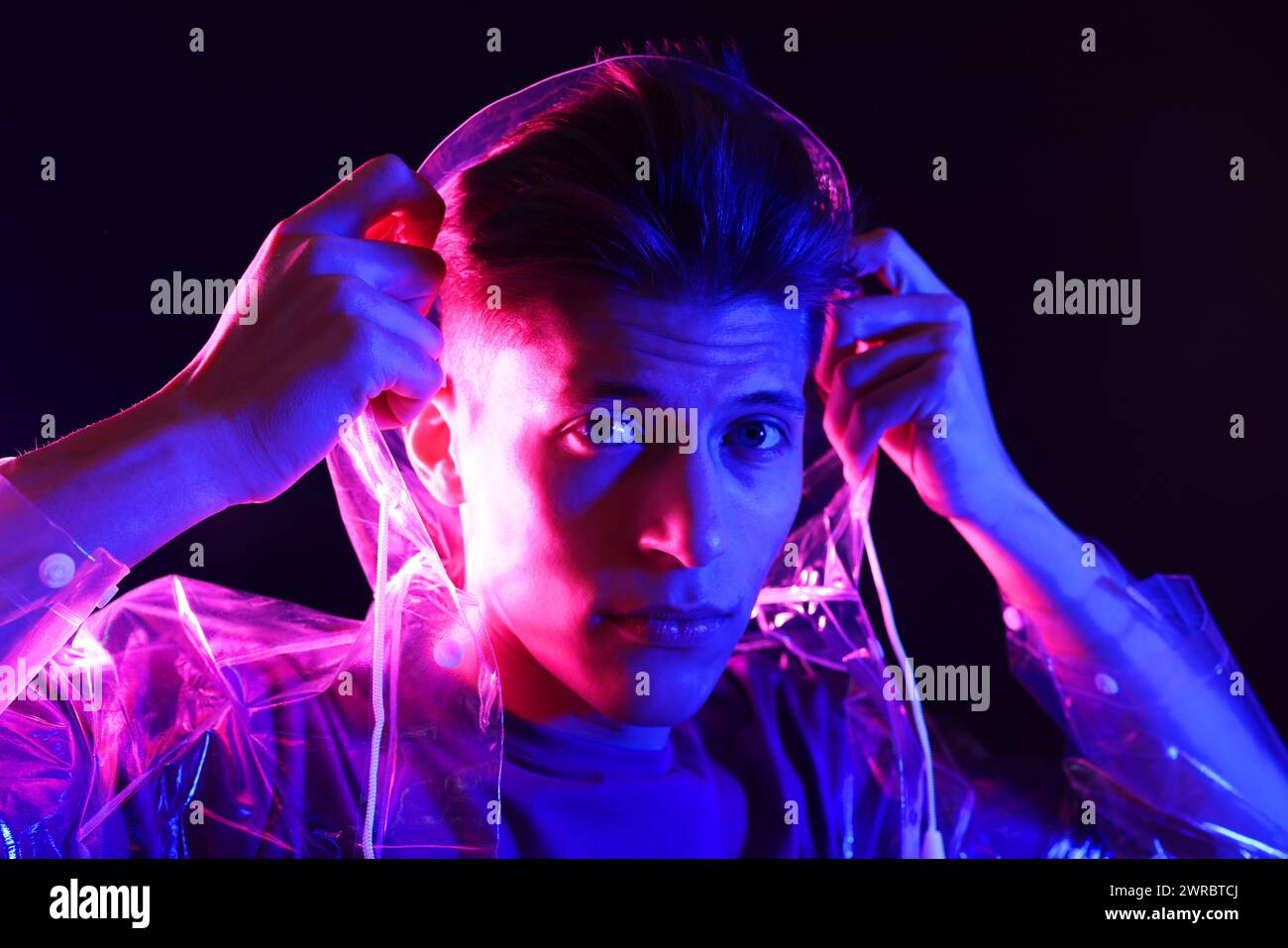 Young man wearing clear coat on dark background in neon lights Stock ...
