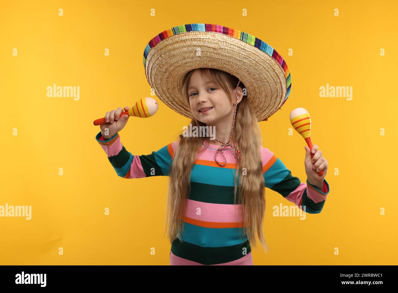 Cute girl in Mexican sombrero hat dancing with maracas on orange ...