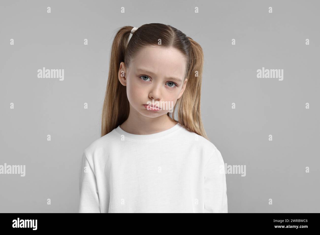 Portrait of sad girl on light grey background Stock Photo - Alamy