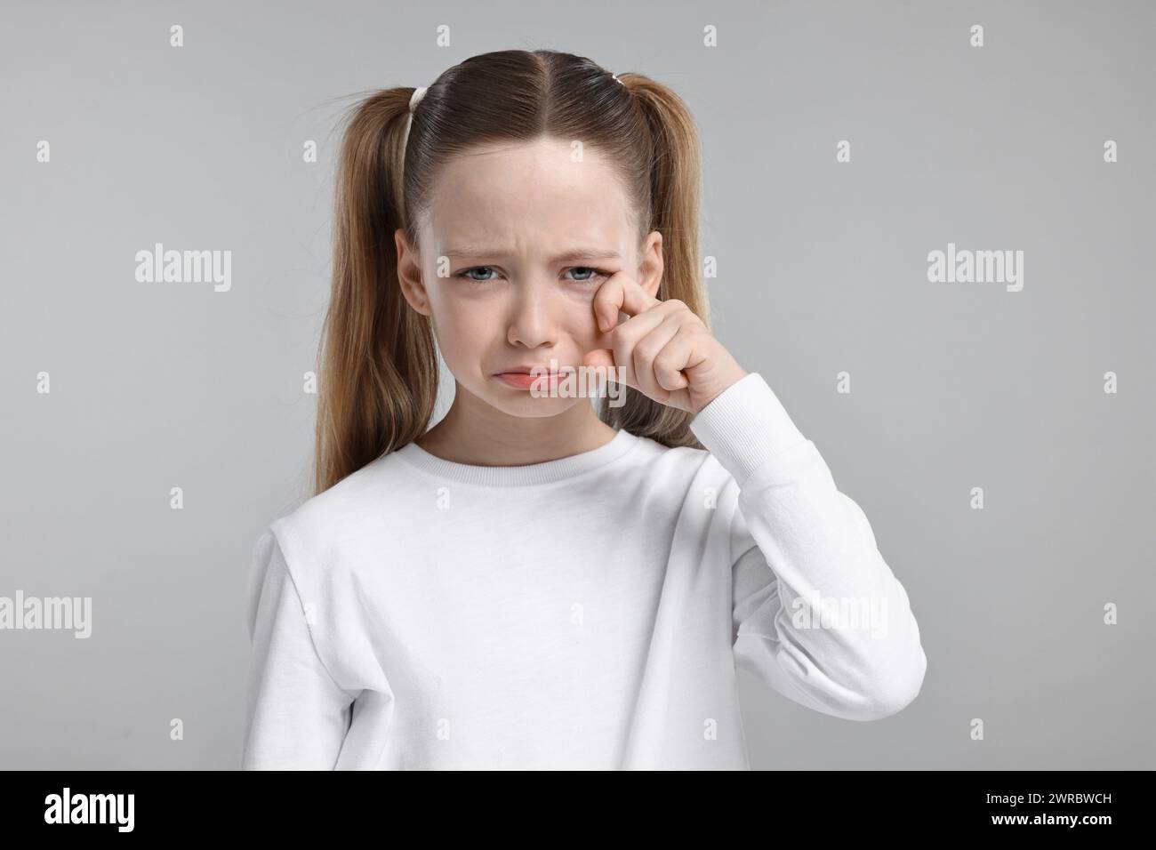 Portrait of sad girl on light grey background Stock Photo - Alamy