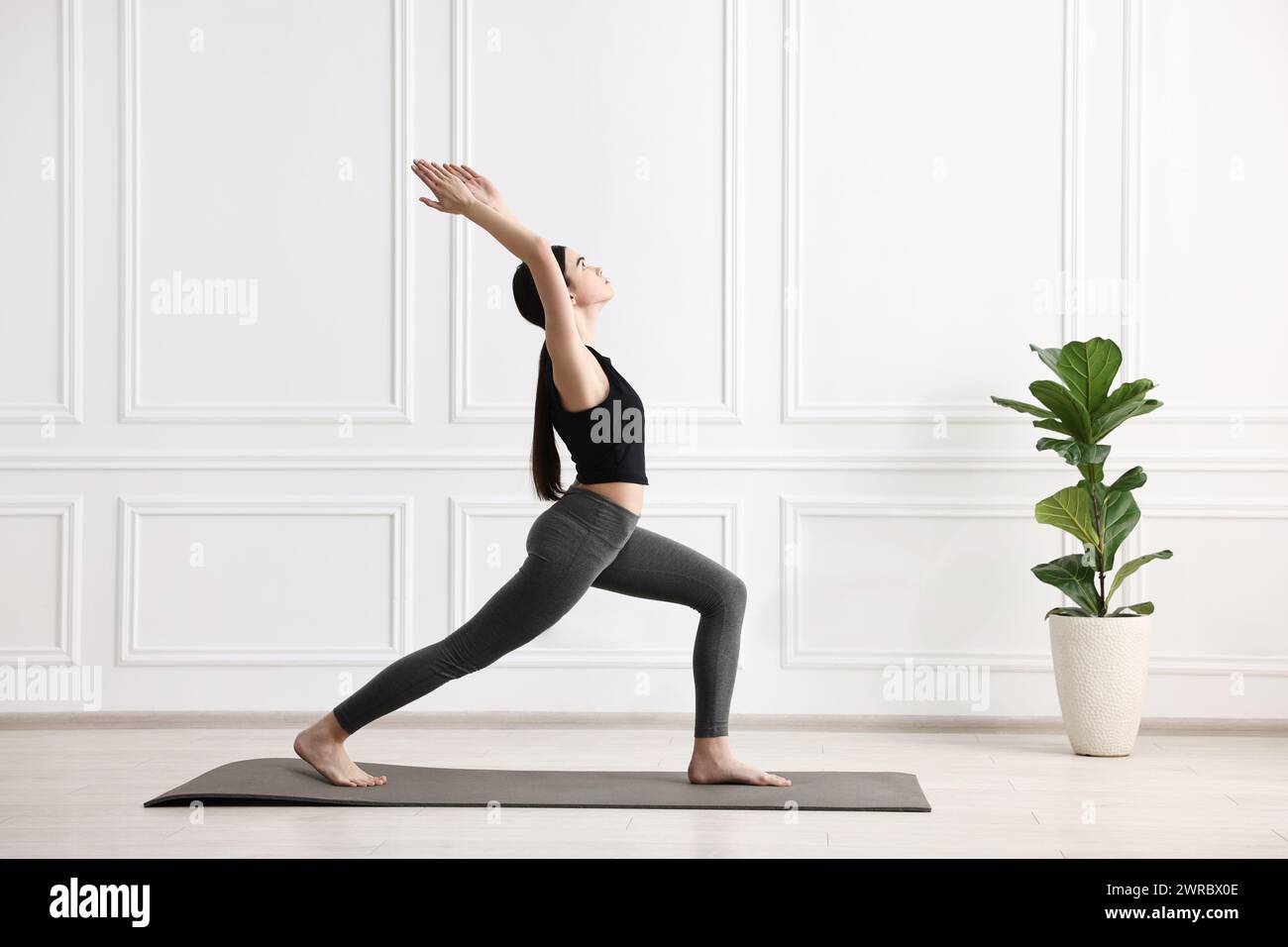 Girl practicing crescent asana on mat in yoga studio. High lunge pose ...