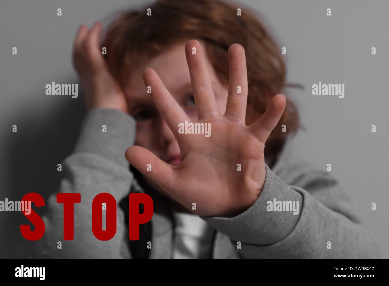 No child abuse. Boy making stop gesture near grey wall, selective focus ...
