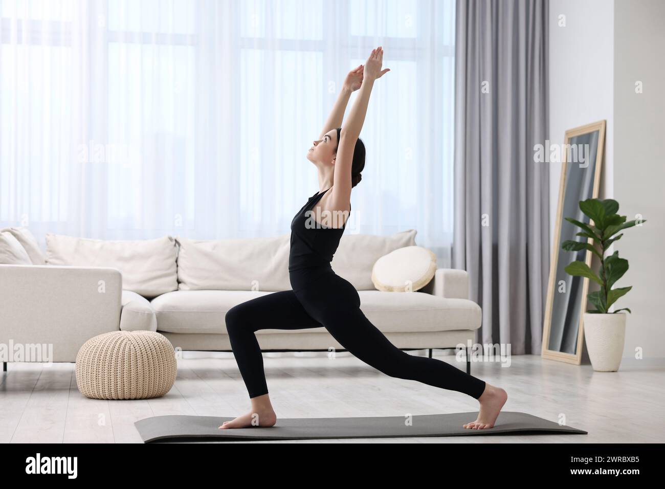 Girl practicing crescent asana on yoga mat at home. High lunge pose ...