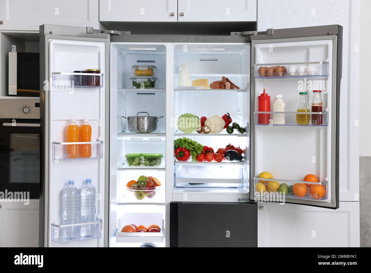 Open refrigerator full of different products in kitchen Stock Photo - Alamy