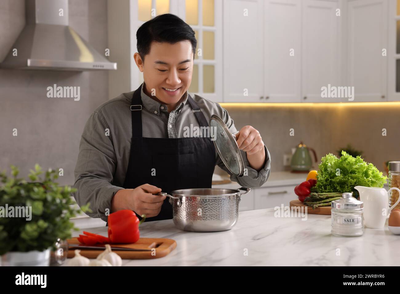 Cooking process. Man with pot at countertop in kitchen Stock Photo - Alamy