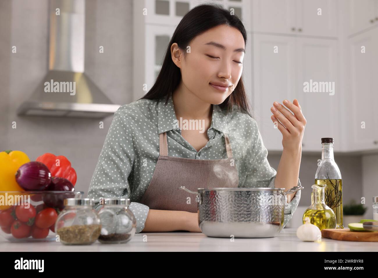 Beautiful woman smelling soup after cooking at countertop in kitchen ...