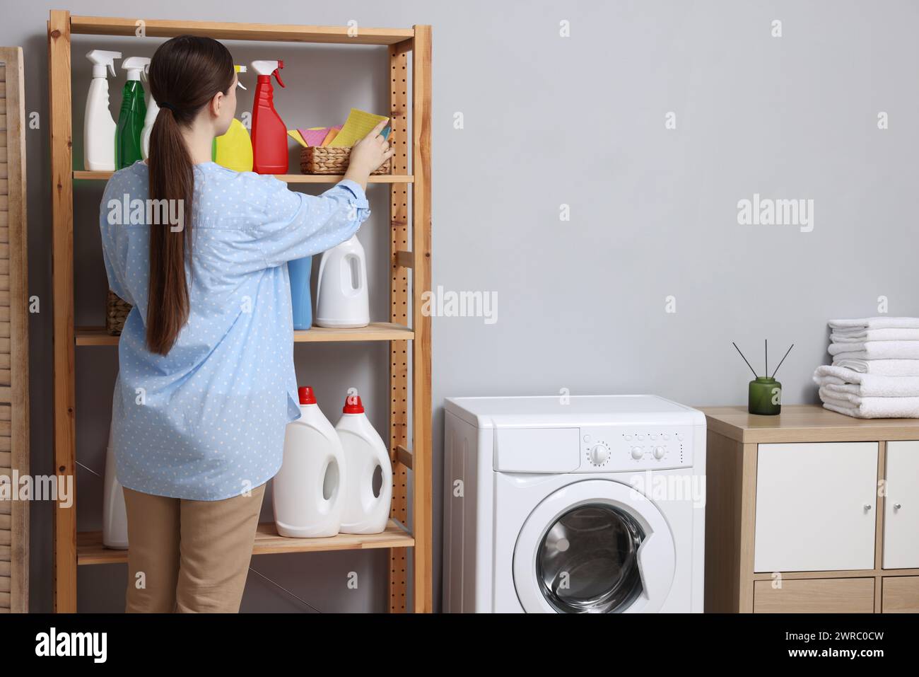 Woman taking cleaning cloth from basket in laundry room Stock Photo - Alamy