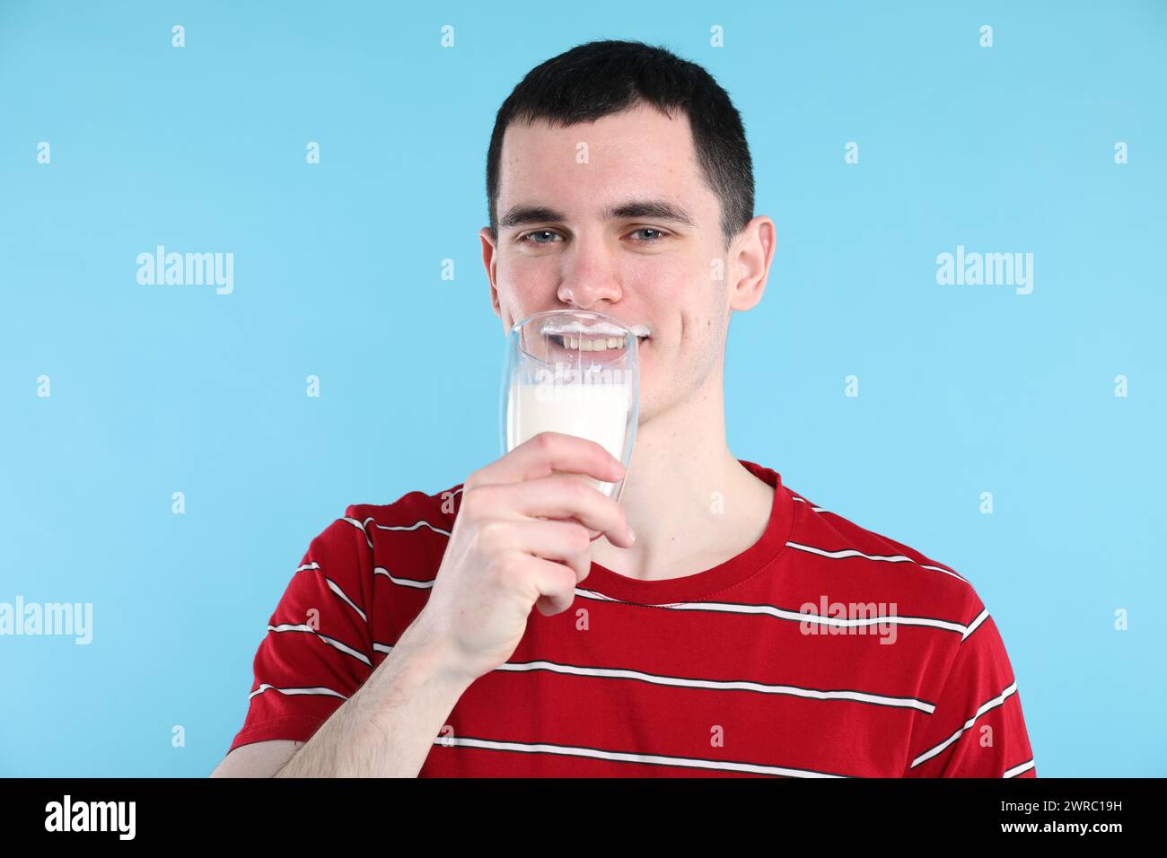 Milk mustache left after dairy product. Man drinking milk on light blue ...