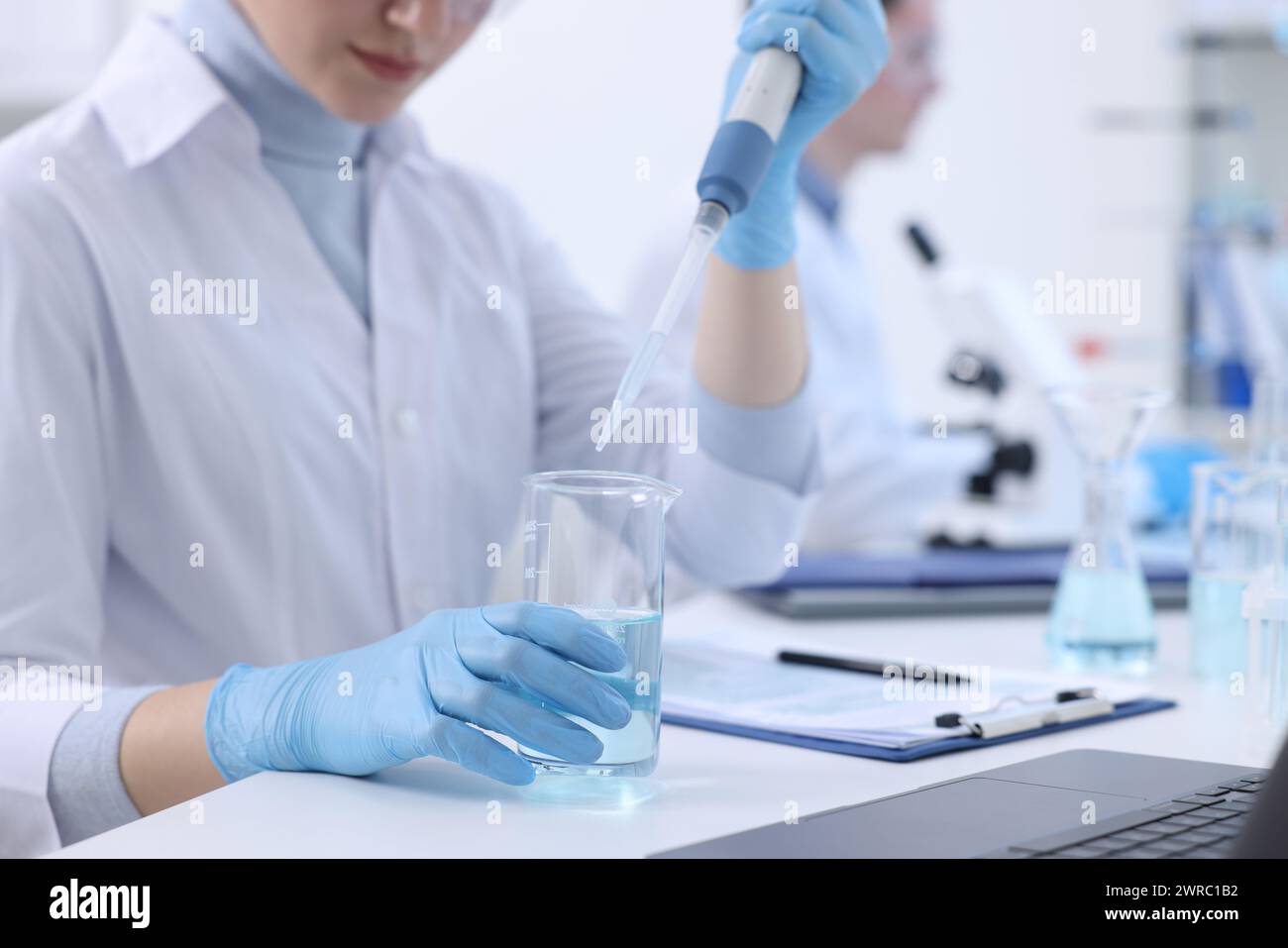 Scientist dripping sample into beaker in laboratory, closeup Stock ...