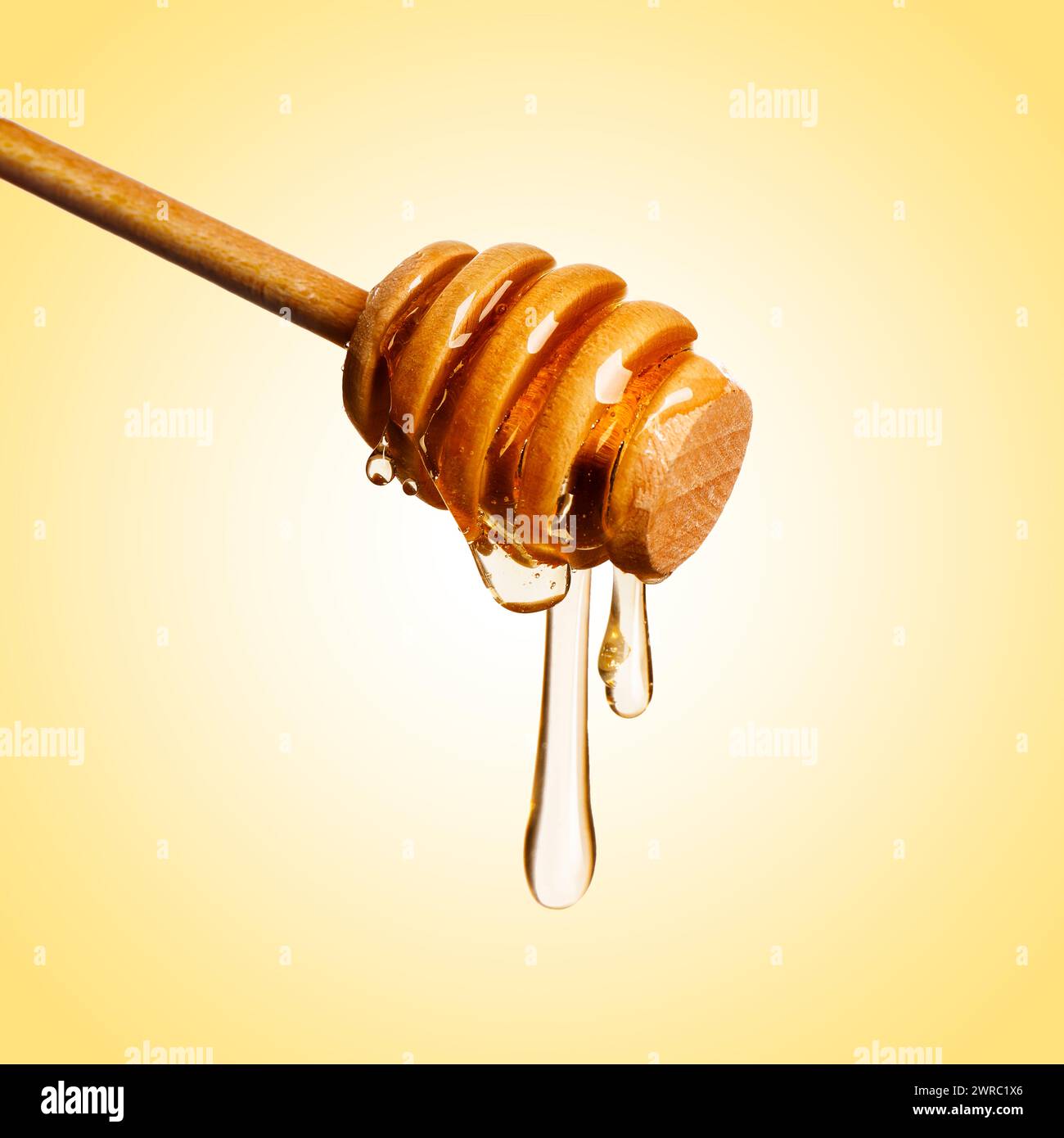 Natural honey dripping from dipper on pale yellow background Stock ...