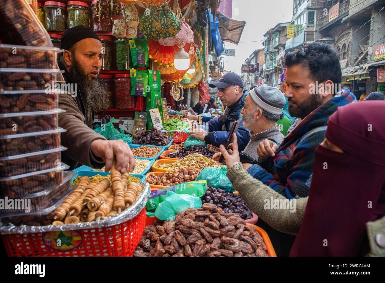 Srinagar, India. 11th Mar, 2024. Kashmiri shopkeeper selling dates and ...