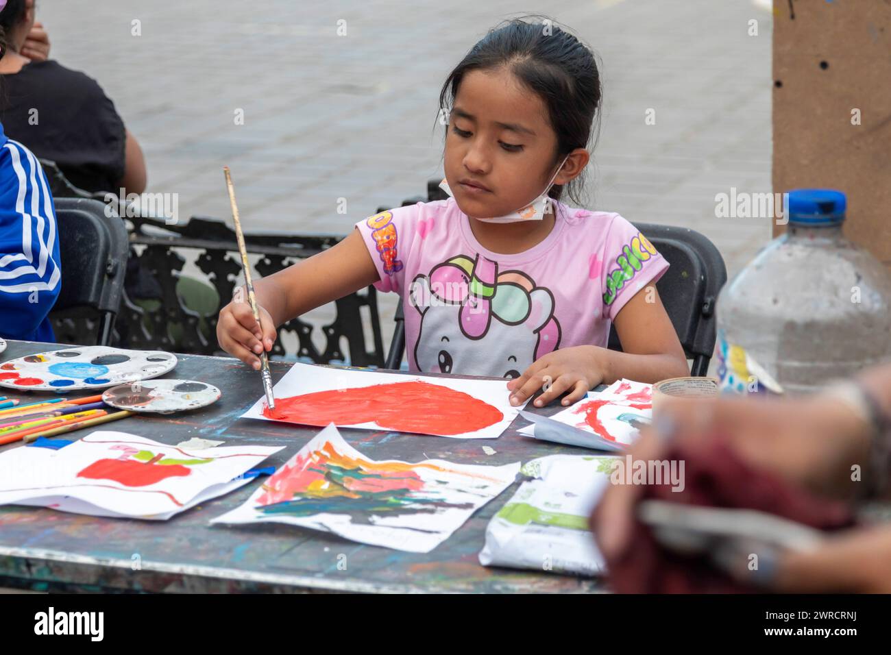 Oaxaca, Mexico - Students painting at a temporary art class in the zocalo. A girl paints a heart ...