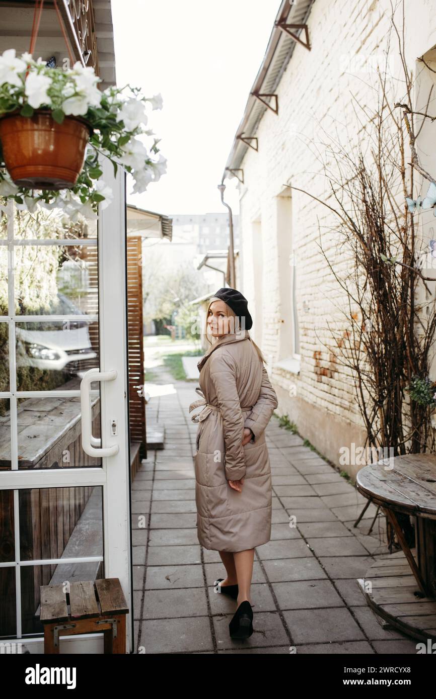A woman strides down a city sidewalk flanking a tall building. Her ...