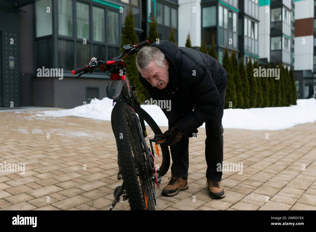 Elderly man checking his bike on the street Stock Photo - Alamy