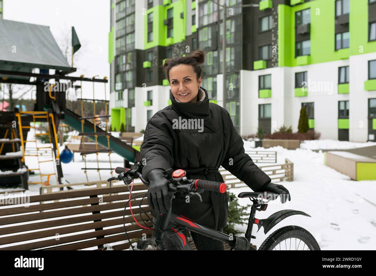 European young woman sat down on a bench to rest during a bike ride ...