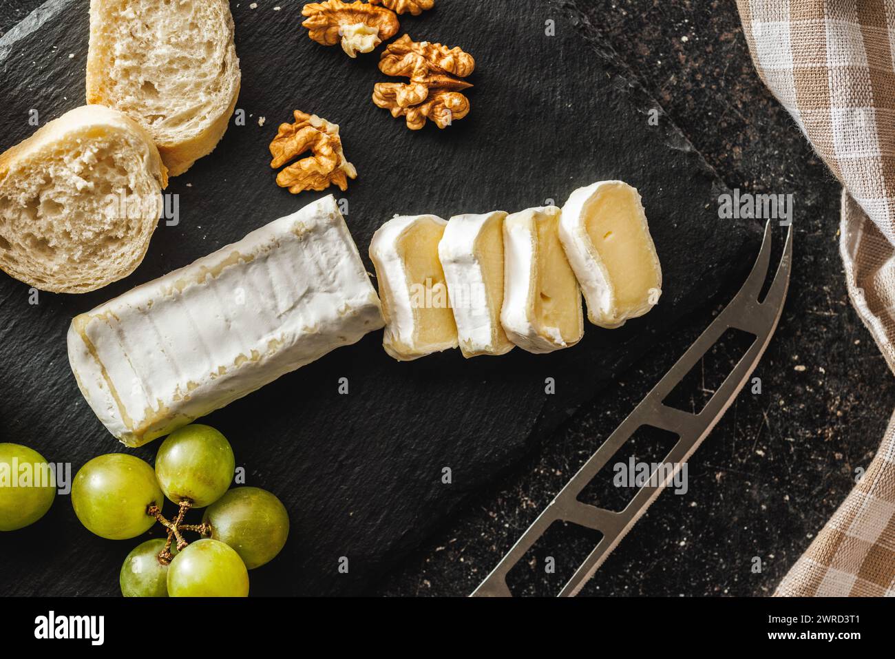 Detailed close-up of a cut Brie cheese accompanied by crisp grapes on a ...
