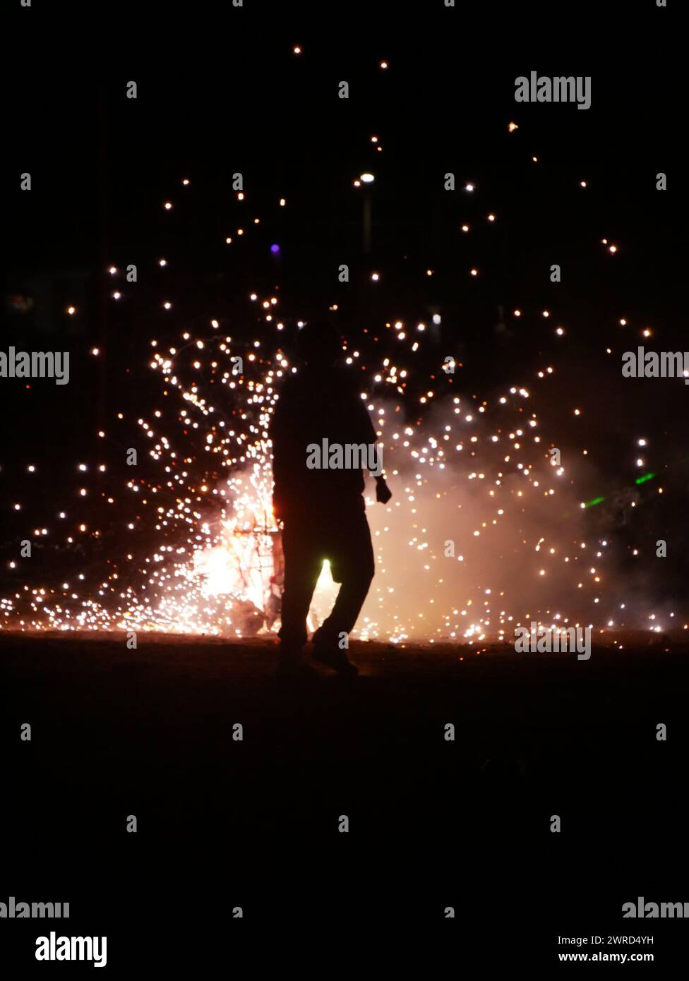 Silhouette of a man walking away from fire with sparkles ahead Stock ...