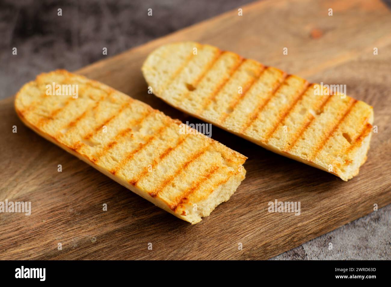 Two pieces of bread with grill marks on them. The bread is cut in half ...