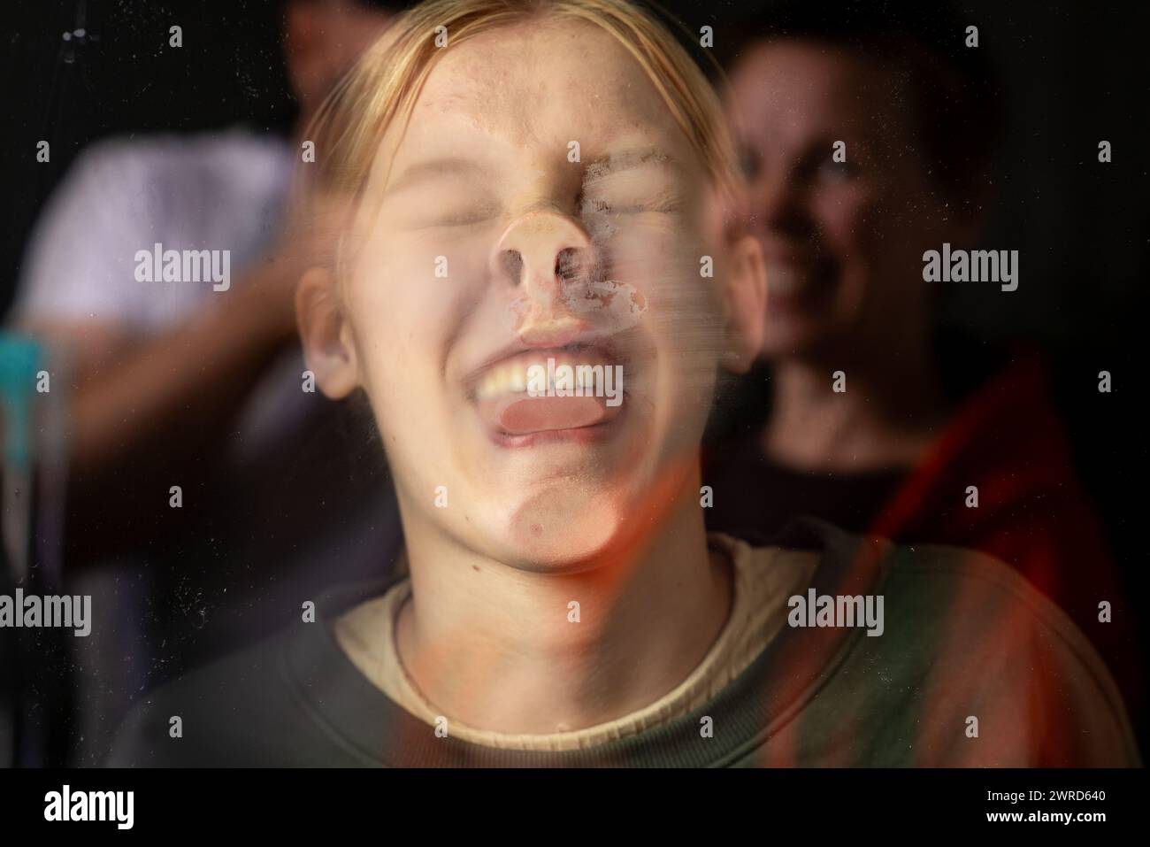 Portrait of a teenage girl through her face pressed against the glass ...