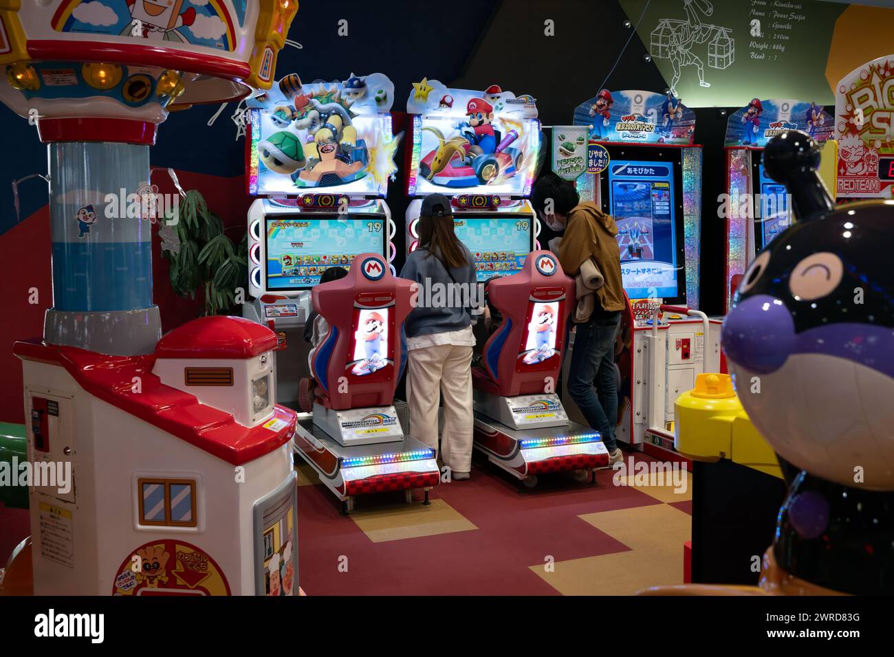 A family playing Mario racing game at an arcade amusement game center ...