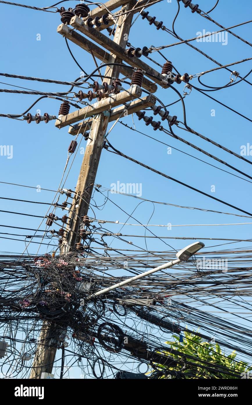 A jumble of electrical and telephone wires attached to a utility pole ...