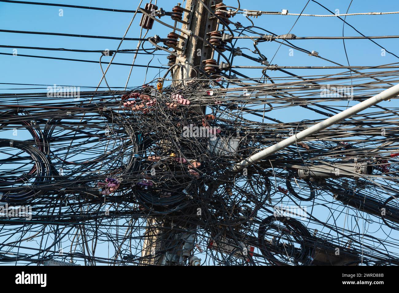 A jumble of electrical and telephone wires attached to a utility pole ...
