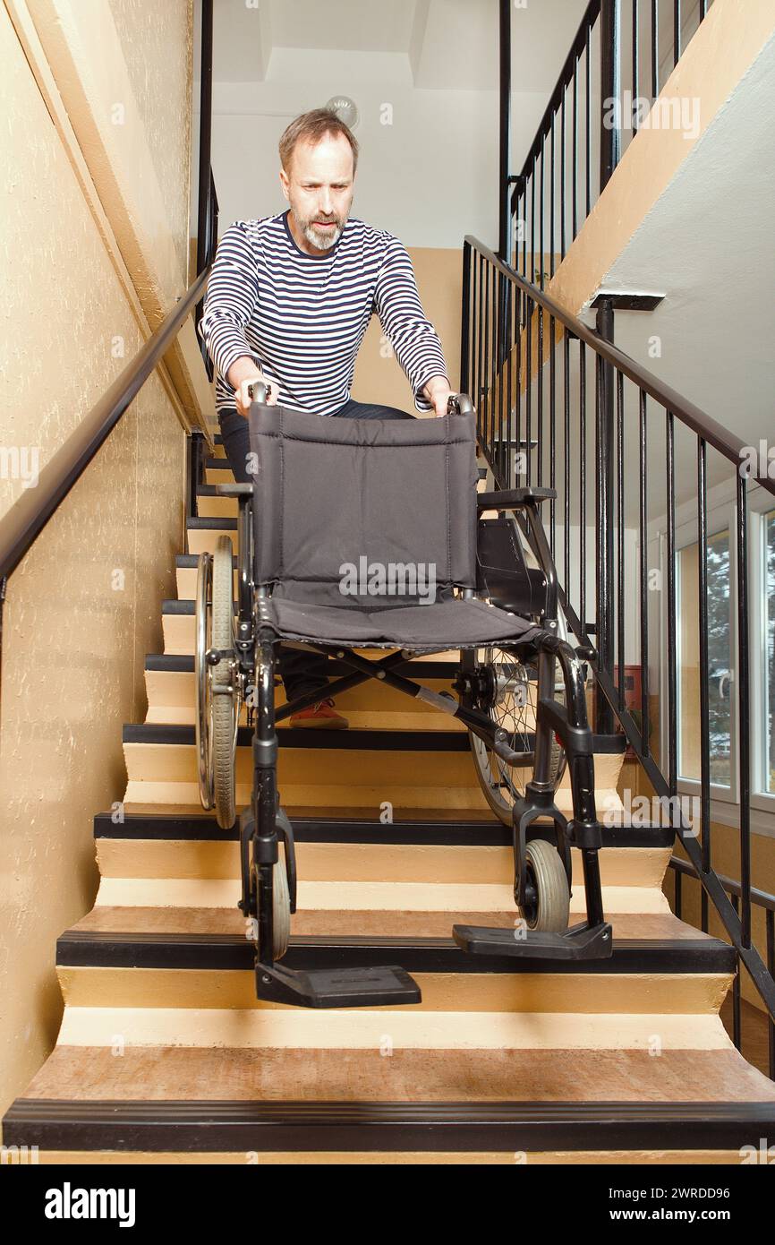 Man helping to move wheel chair downstairs in prefab house Stock Photo ...