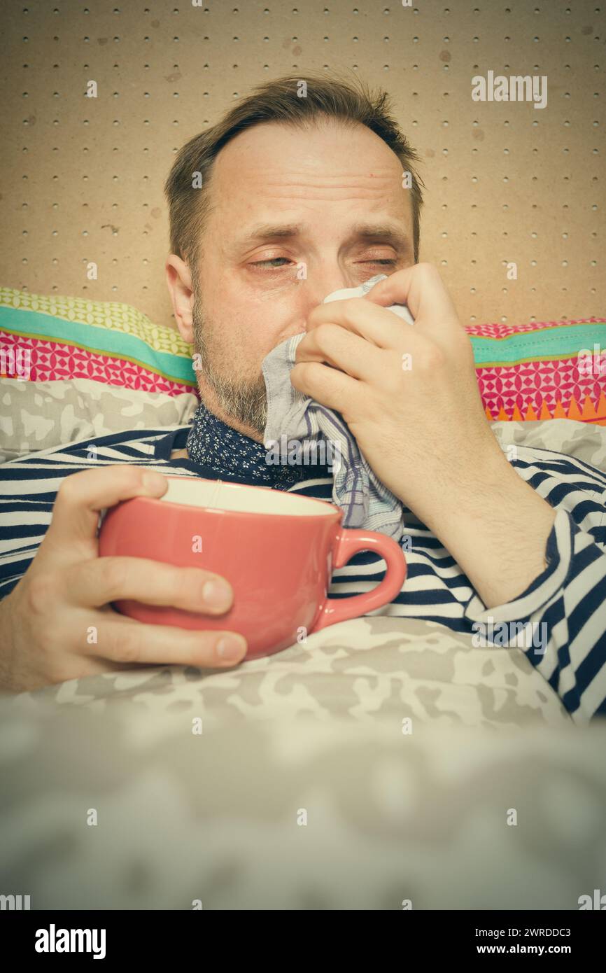 Mature sick man drinking hot tea from cup alone at home in bed Stock ...