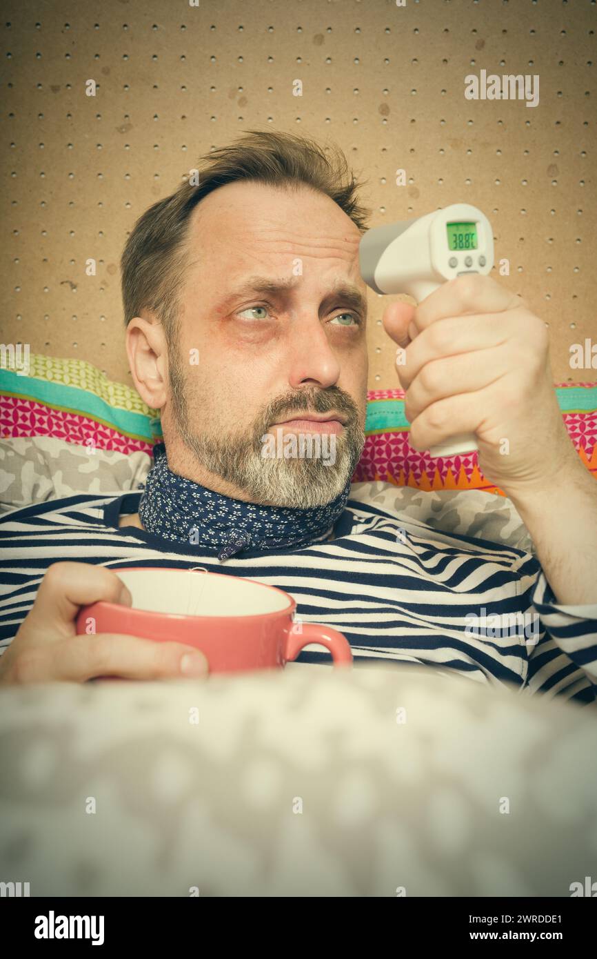 Mature sick man checking body temperature with thermometer Stock Photo ...