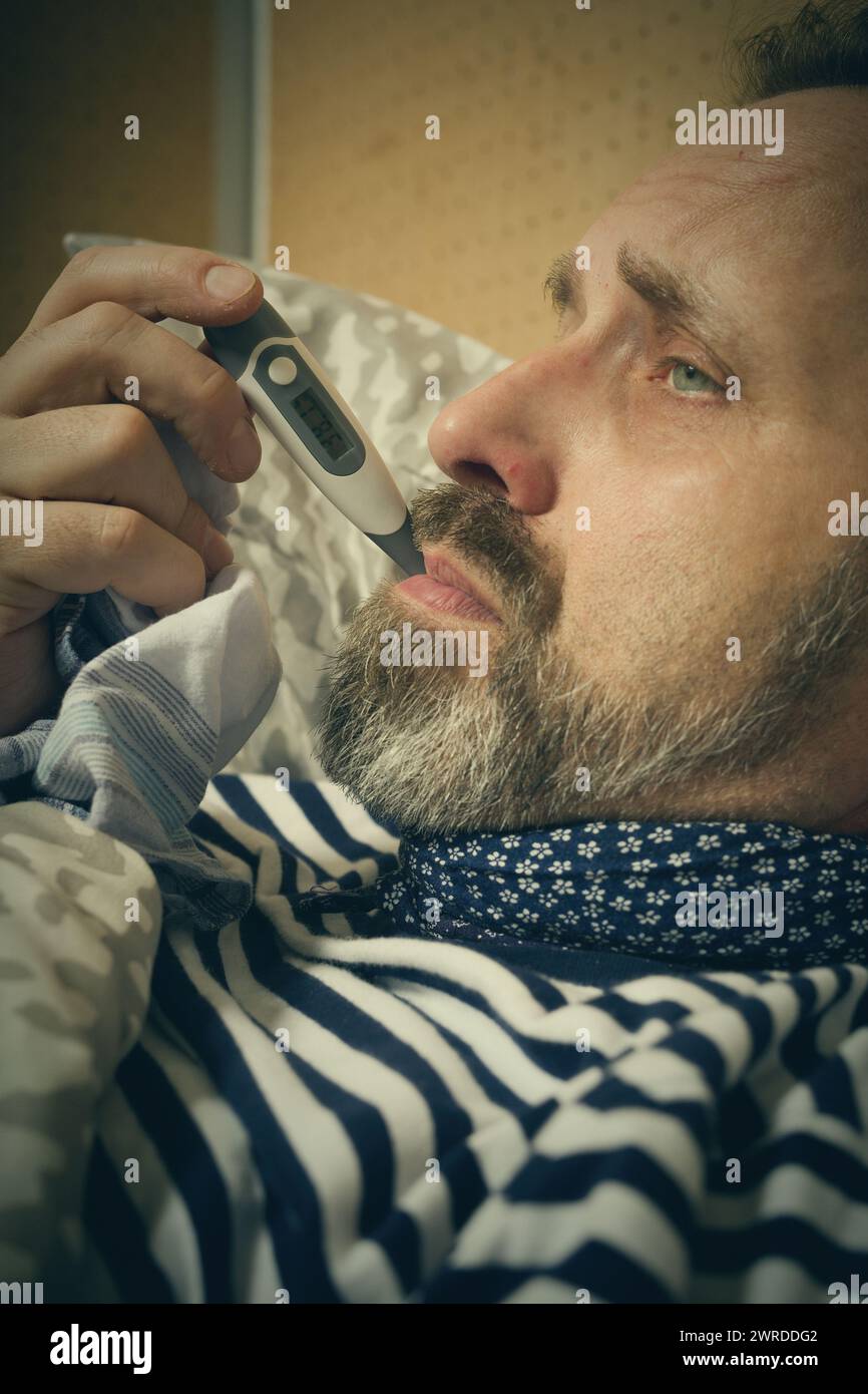 Mature sick man checking body temperature with thermometer Stock Photo ...