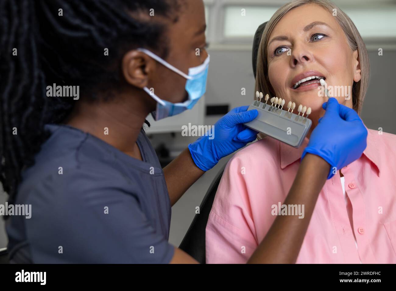 Woman dentist holding dental teeth shade guide chart choosing right ...