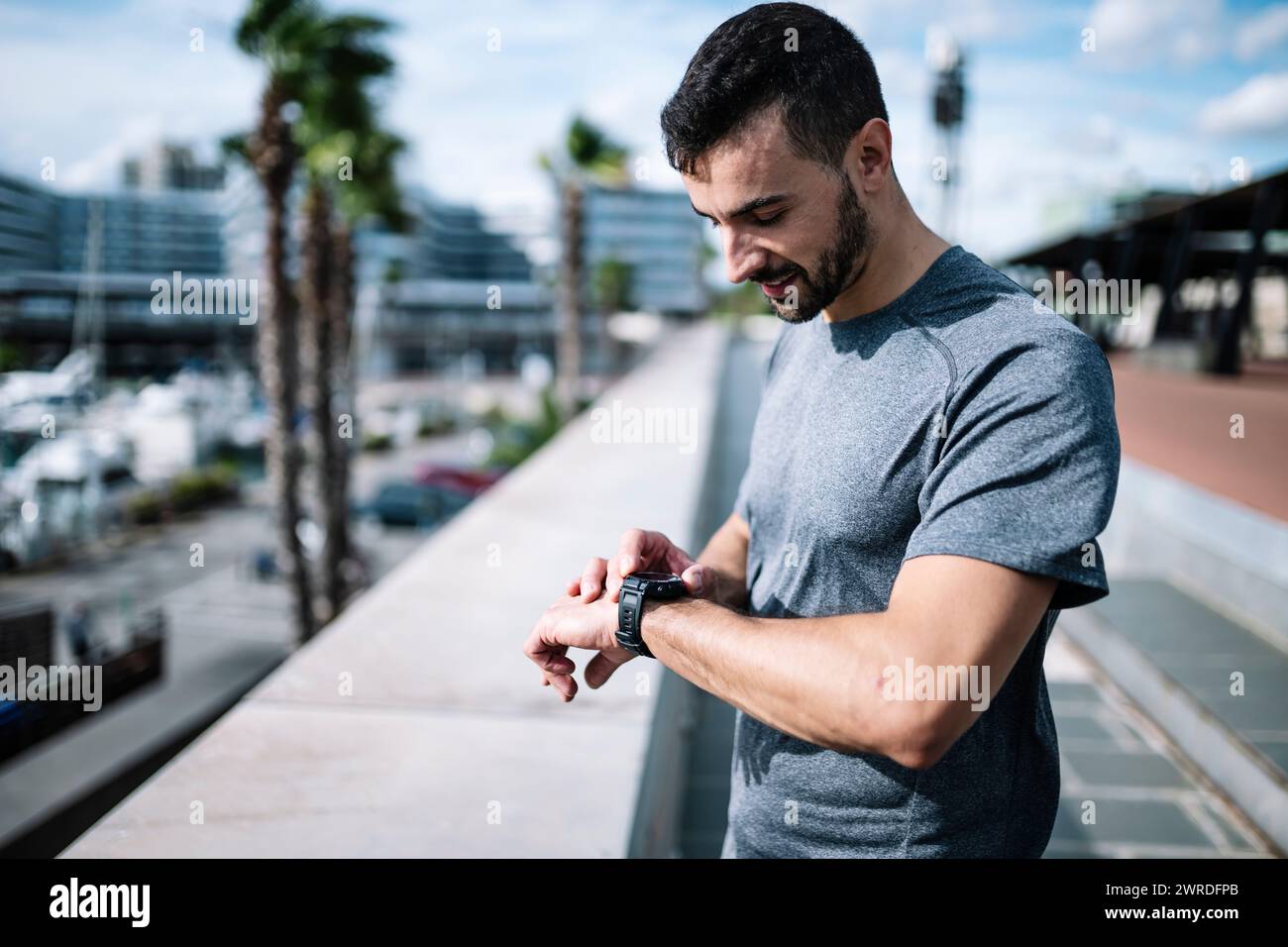 Active man looking swatch during exercise outside. Fitness male looking ...