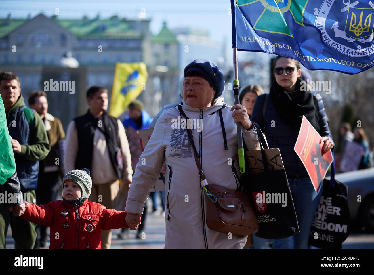 Senior Ukrainian woman walks with a flag of Coastal Guard of Ukraine on ...
