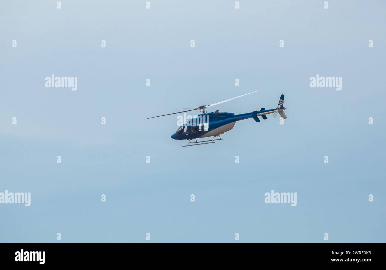A large, blue helicopter is flying against the blue sky Stock Photo - Alamy
