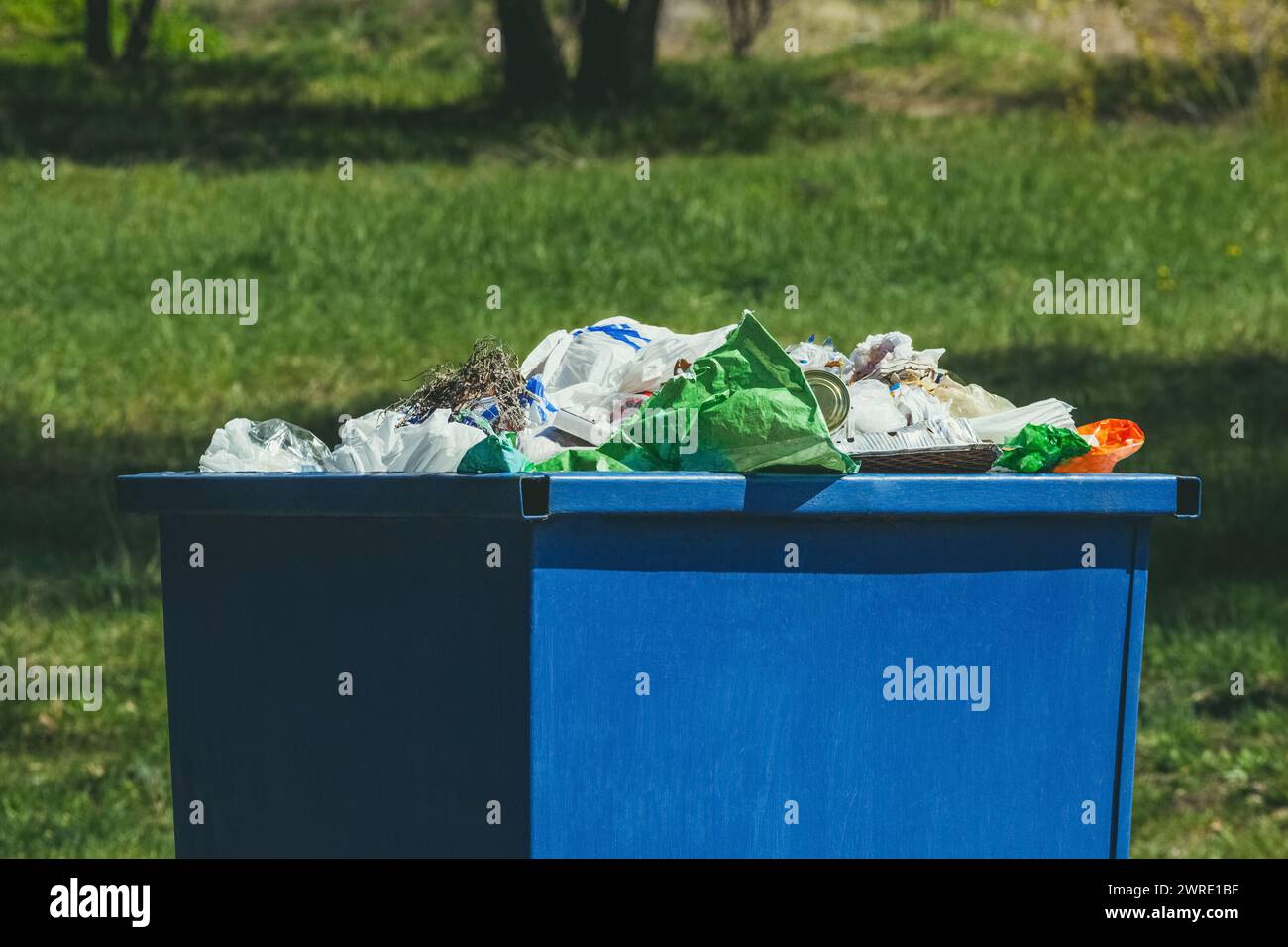 A crowded blue trash can on the street. Environmental pollution Stock ...