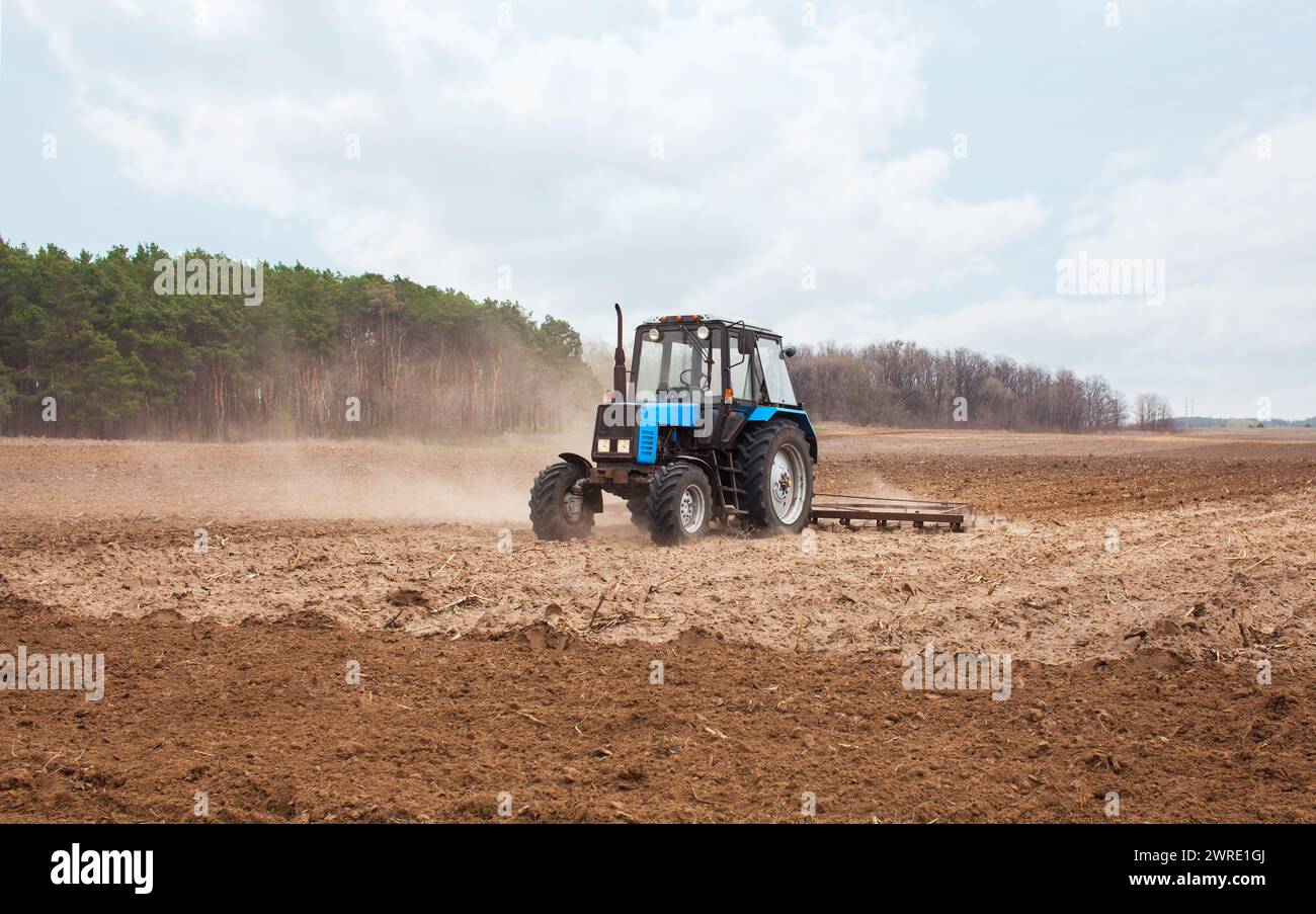 A spring day the tractor goes and pulls a plow plowing a field before ...