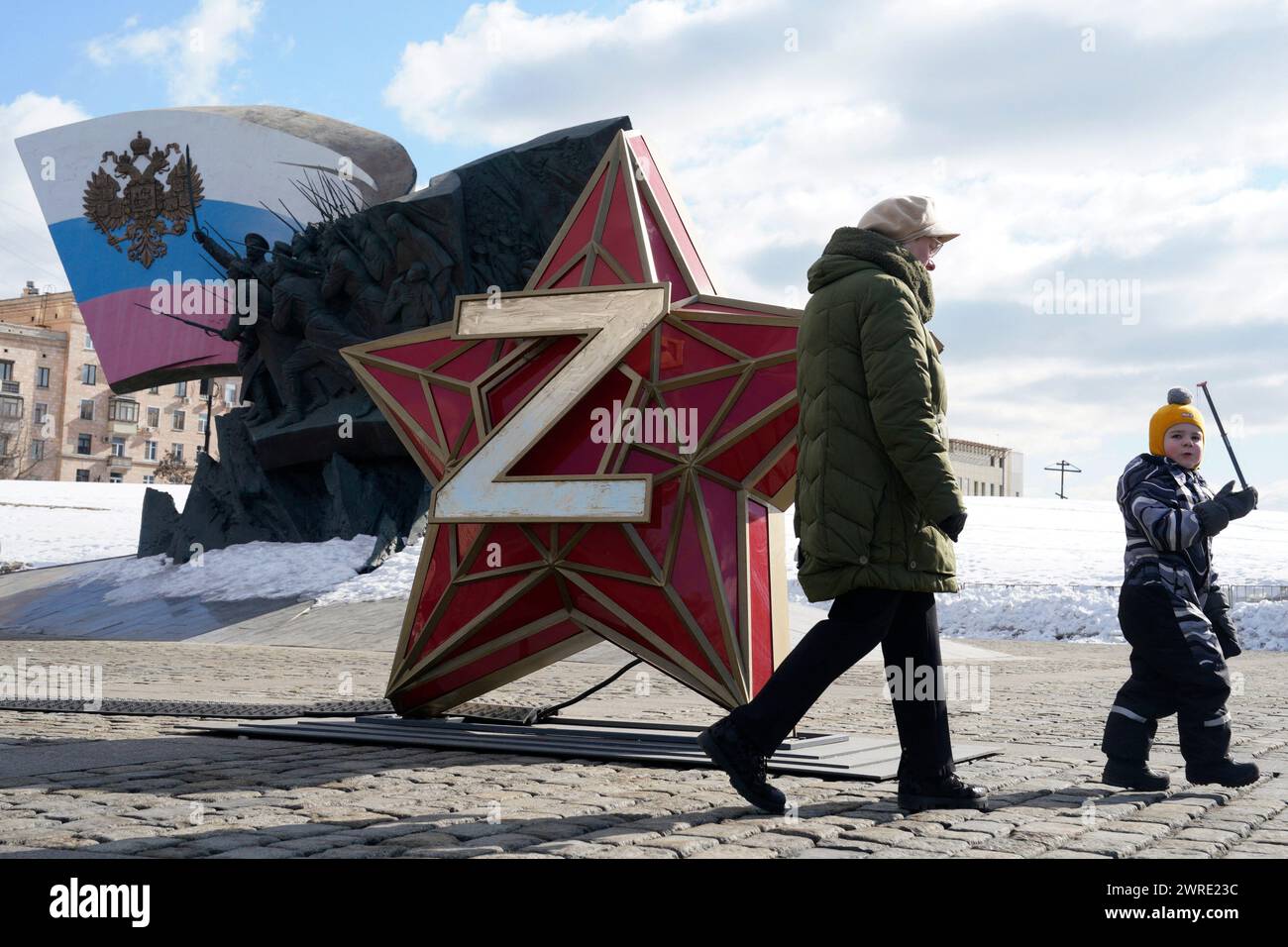 A woman with a child walks past a Kremlin Star, bearing Z letter, an ...