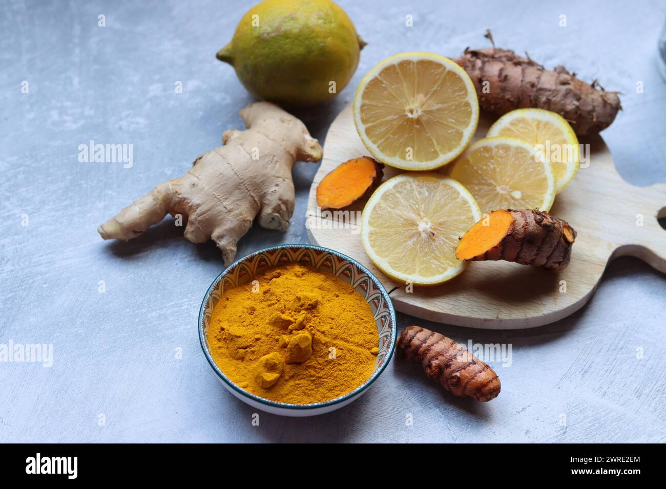 Turmeric powder in bowl and fresh turmeric root on textured background ...