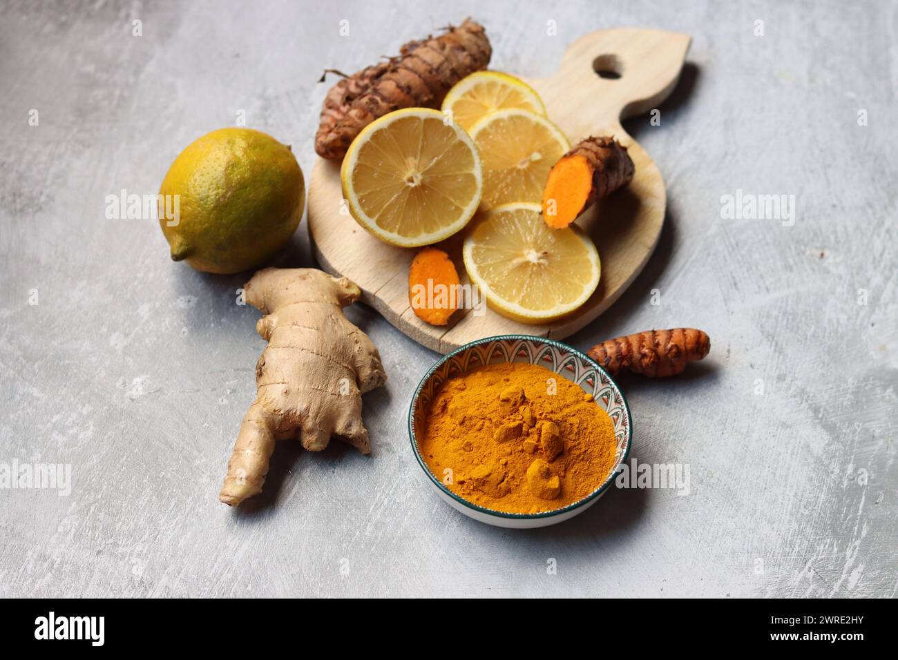 Turmeric powder in bowl and fresh turmeric root on textured background ...