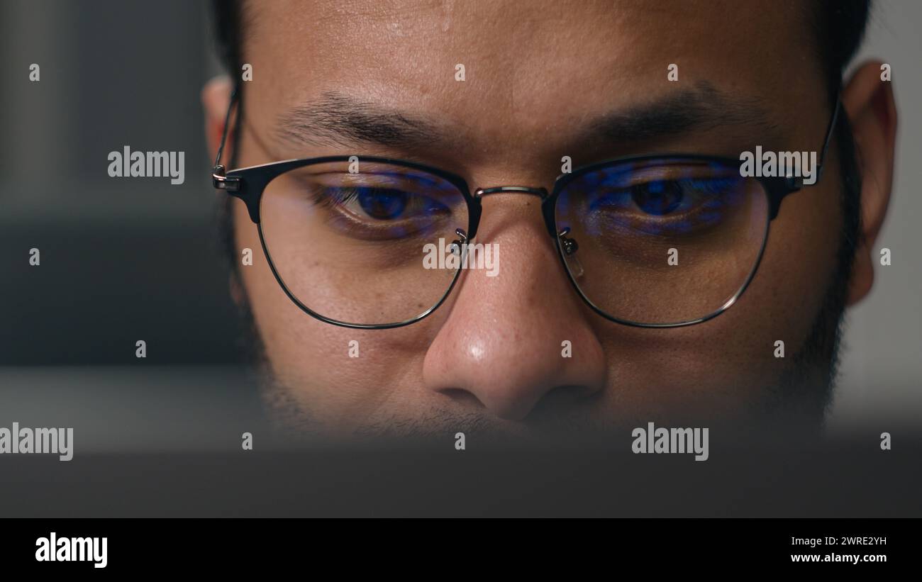 Close up concentrated focused male eyes in eyeglasses looking at laptop ...