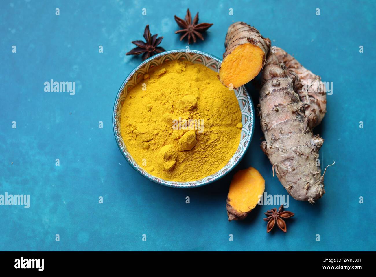 Turmeric powder in bowl and fresh turmeric root on textured background ...