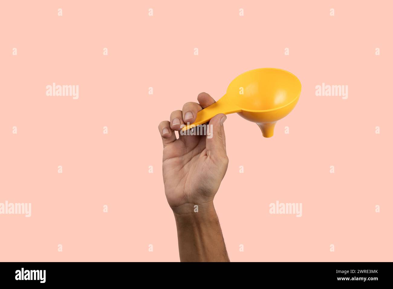 Black male hand holding a yellow kitchen funnel isolated, pink ...