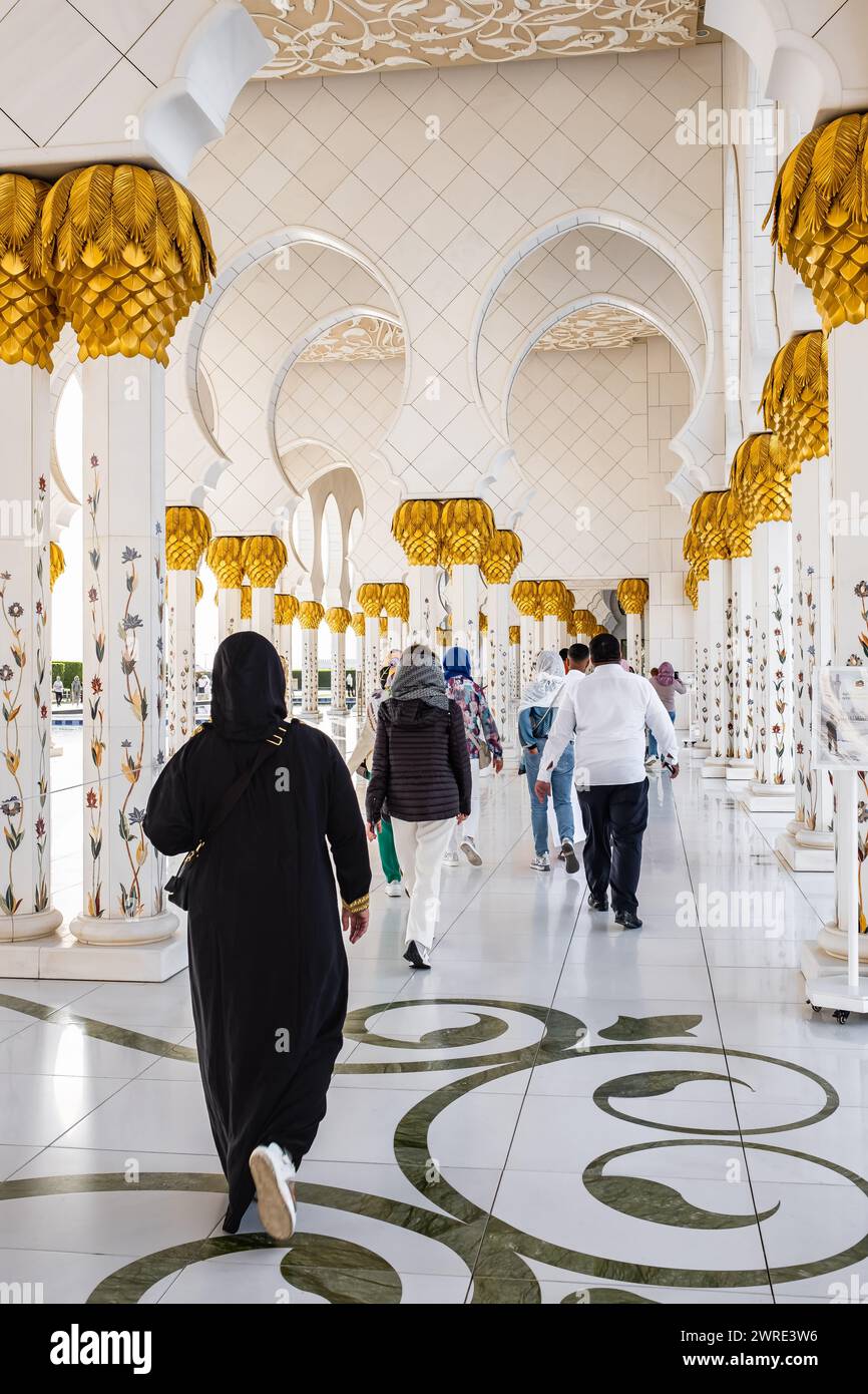 People visit Sheikh Zayed Grand Mosque. Traditionally dressed tourist ...
