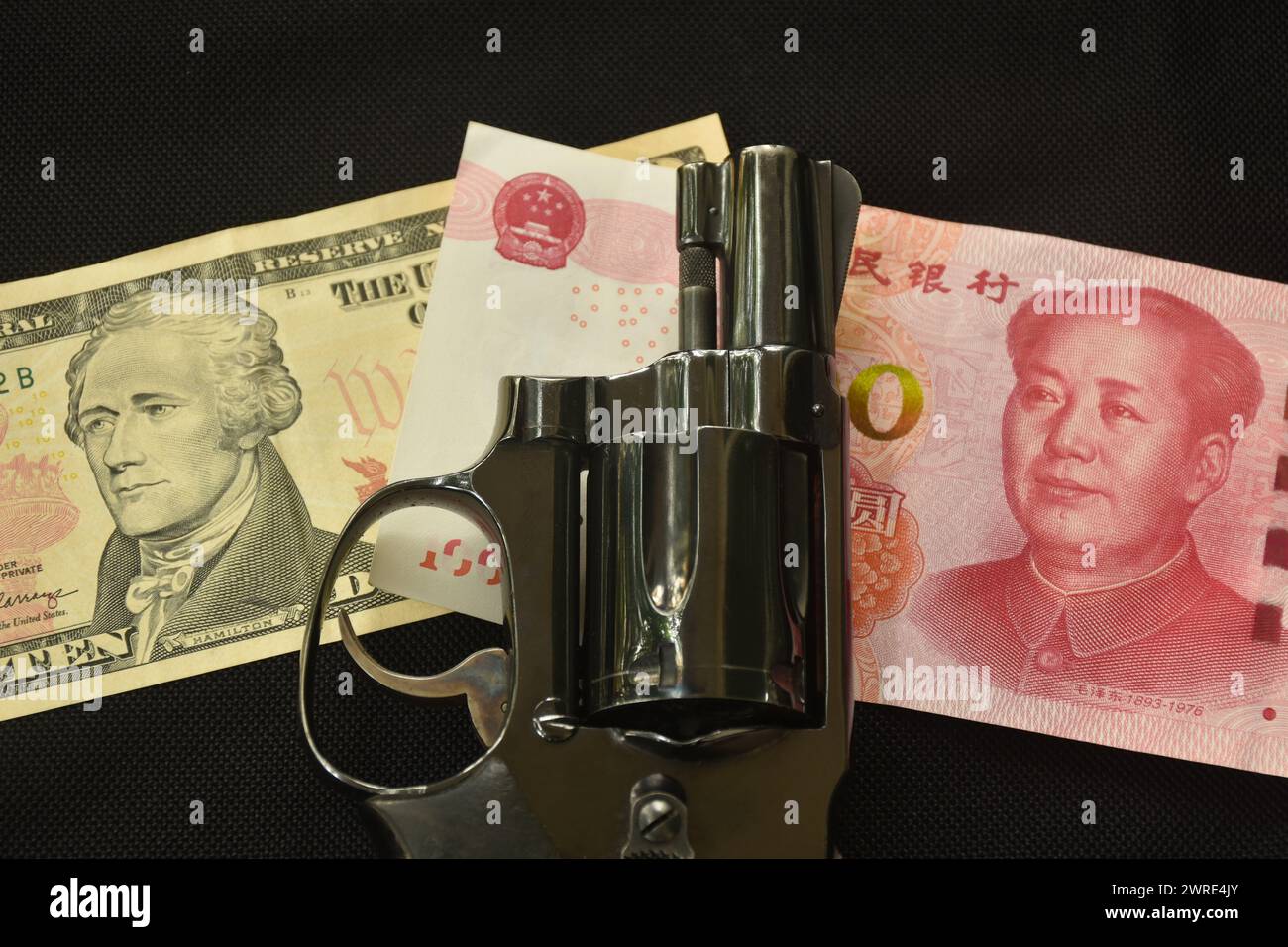 gun with yuan and dollar paper currency concepts trade war on black ...