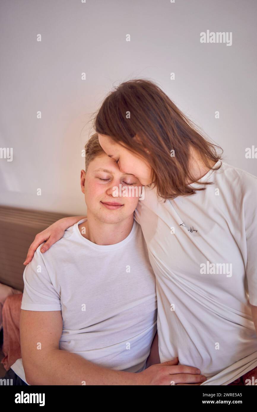 young couple in home clothes gently hug in the living room, minimalism ...