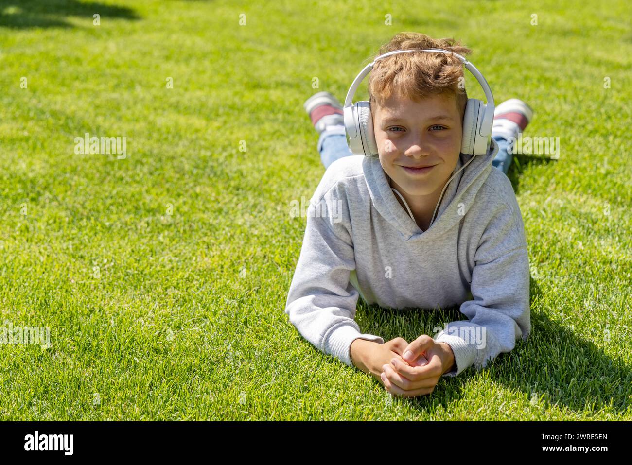 A boy relaxing on grass, listening to music with headphones Stock Photo ...